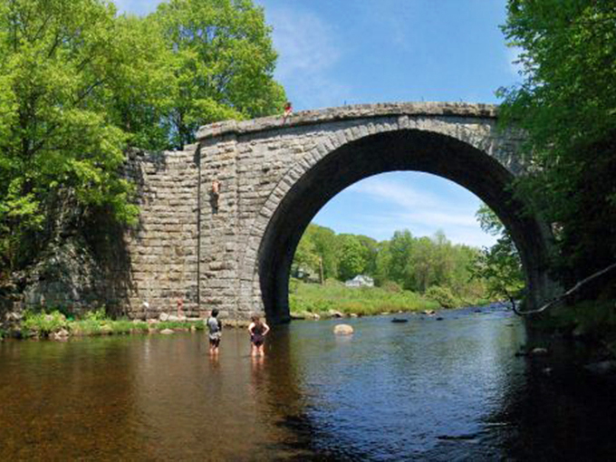 This stone arch bridge has stood for generations, proving that some investments truly last forever. Kids still cool off underneath just as their grandparents once did.