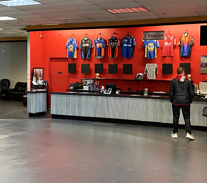 Racing jerseys frame the check-in counter like trophies, silently promising newcomers: "You could be legendary too."