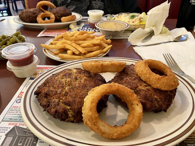 Crab cakes with personality alongside onion rings that could double as golden halos. Delaware's seafood tradition meets comfort food perfection.