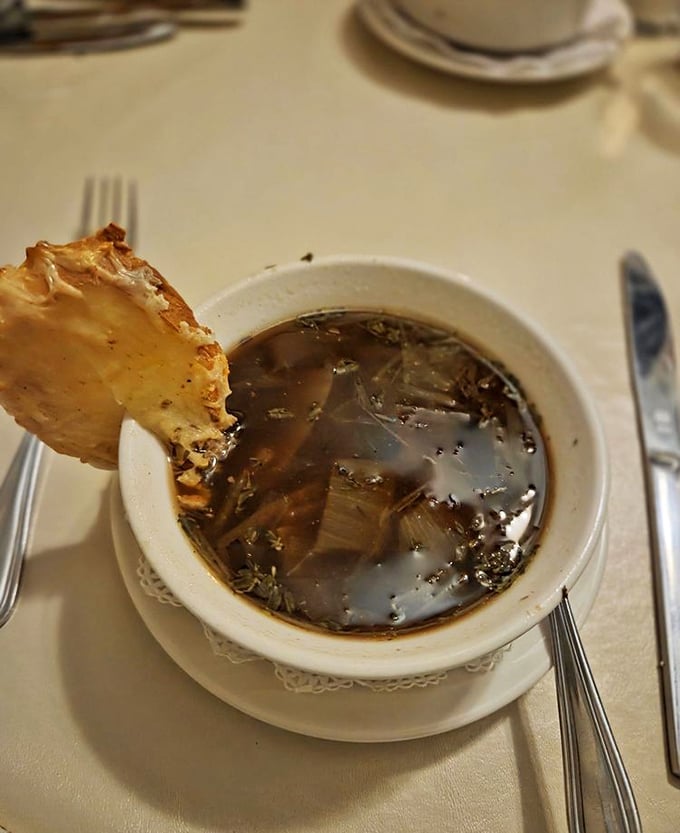 French onion soup that's worth the inevitable cheese pull photo. This savory broth topped with a crusty island of bread and molten cheese warms from the inside out.