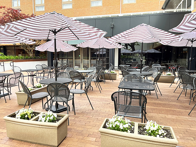 Striped umbrellas create an outdoor oasis where summer brunches stretch lazily into afternoon, like the weekend itself.