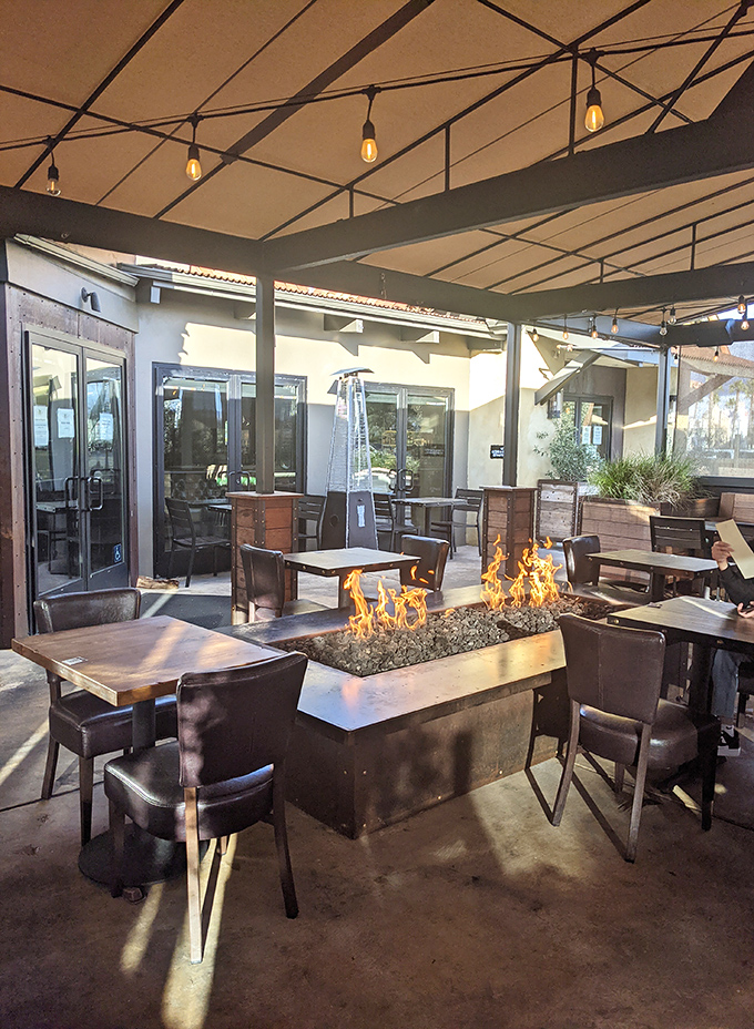 Fire pits and comfortable seating create an outdoor oasis where California evenings stretch deliciously into night, one sip and bite at a time.