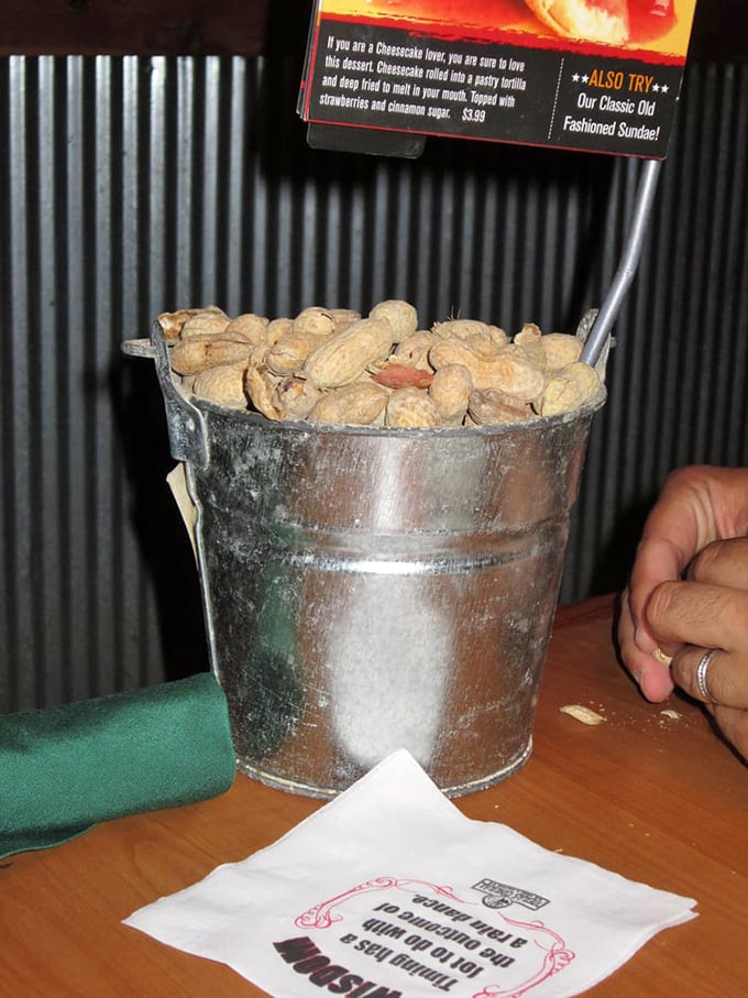 The humble bucket of peanuts—nature's appetizer and floor decoration system rolled into one brilliant conversation starter.