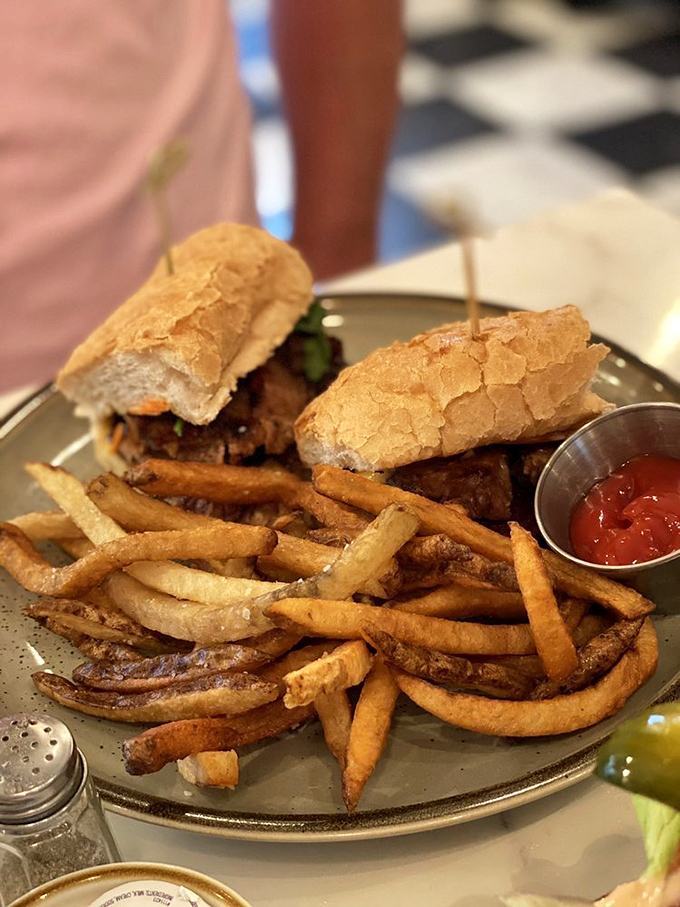 A sandwich that demands two hands and zero distractions&mdash;crispy fries standing guard around what appears to be banh mi perfection.