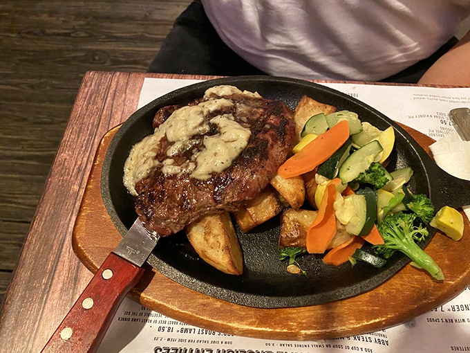 A properly cooked steak on a sizzling platter with a pat of melting compound butter—theater you can eat with a knife and fork.