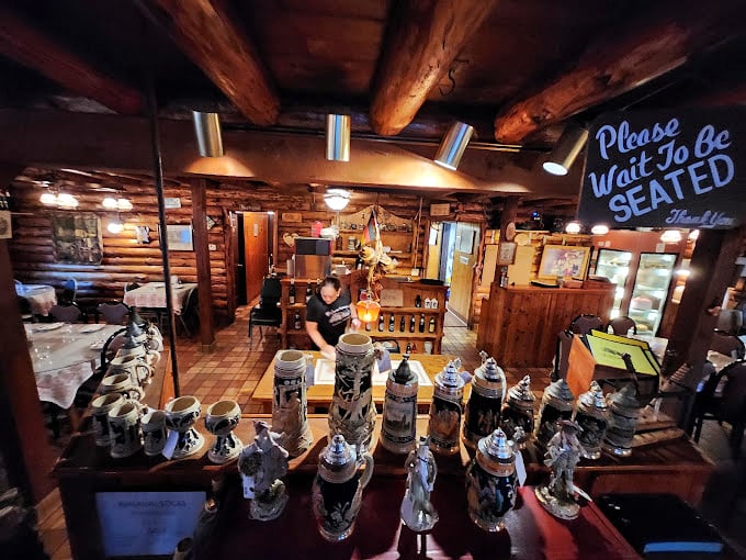 The interior welcomes you with authentic German charm and a "Please Wait To Be Seated" sign. Beer steins stand at attention, ready for their moment.
