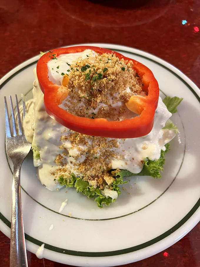 A stuffed pepper that's having an identity crisis as a gourmet dish. Sitting on a bed of lettuce like it's posing for a food magazine cover.