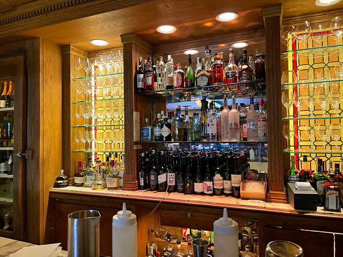 Behind the bar, a stained glass backdrop transforms bottle silhouettes into a cathedral of spirits and possibilities.