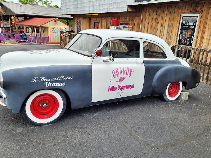 The vintage police cruiser emblazoned with "To Serve and Protect Uranus" perfectly captures the juvenile humor that permeates this entire attraction.