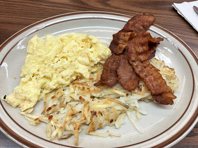The classic American breakfast in its purest form: fluffy scrambled eggs, crispy hash browns, and bacon cooked exactly how you asked.