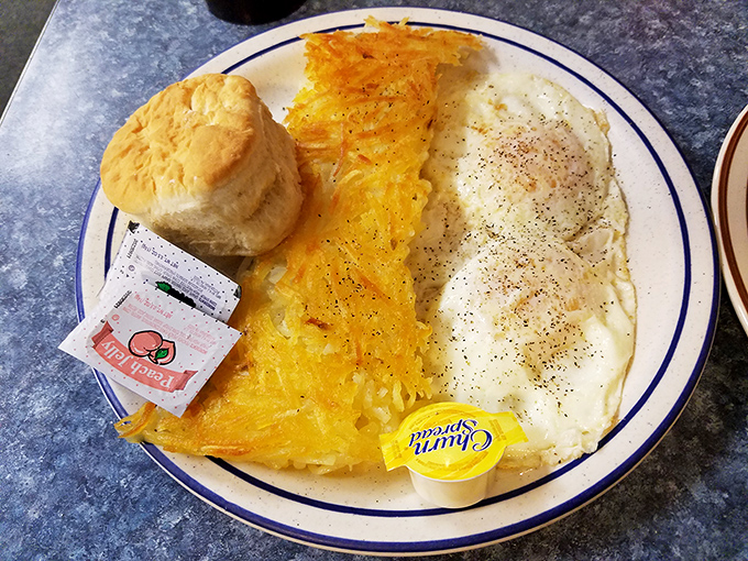 The holy trinity of diner breakfast: golden hashbrowns, eggs with just-right yolks, and a biscuit standing tall with butter potential.