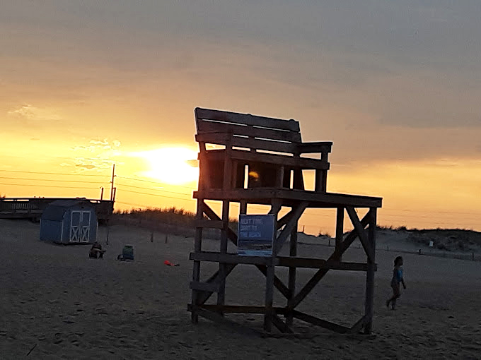 Sunset paints the lifeguard stand in golden hues, transforming a practical necessity into coastal artwork worthy of a postcard.