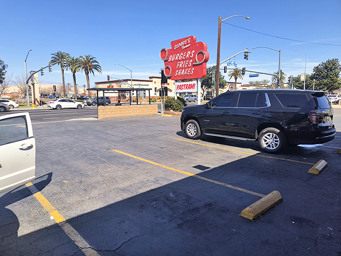 That vintage sign stands tall against the California sky, a red beacon calling hungry travelers like a lighthouse guides ships to safe harbor.