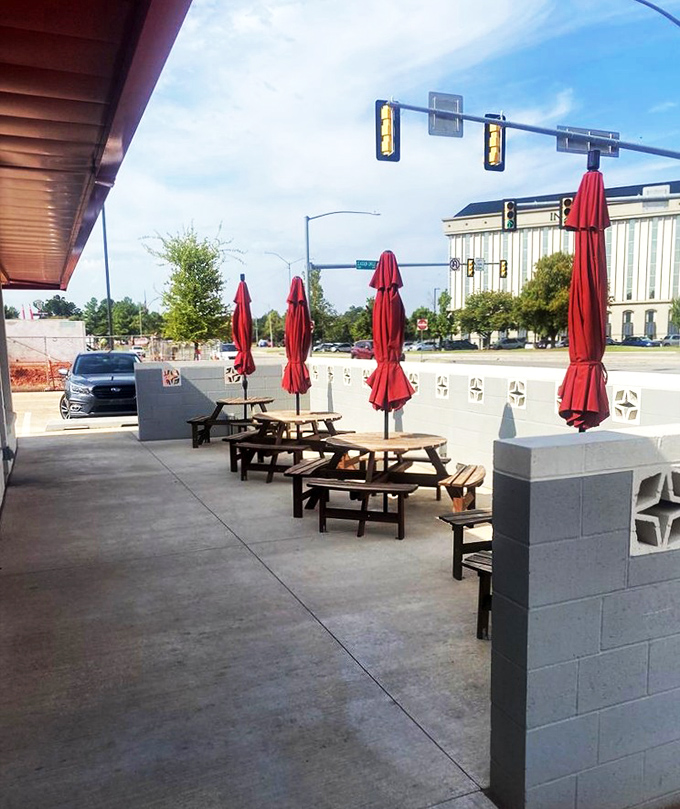 Red umbrellas stand at attention on the patio, where outdoor dining offers a front-row seat to Oklahoma City's bustling urban landscape.