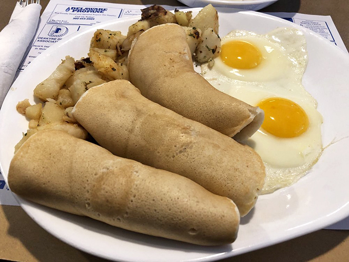 Those golden-brown rolled pancakes aren't just breakfast, they're edible scrolls of happiness alongside perfectly cooked sunny-side-up eggs.