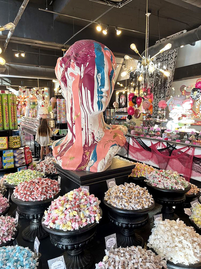 The multi-colored abstract mannequin stands guard over the candy kingdom, like a sweet sentinel designed by Picasso after a sugar binge.