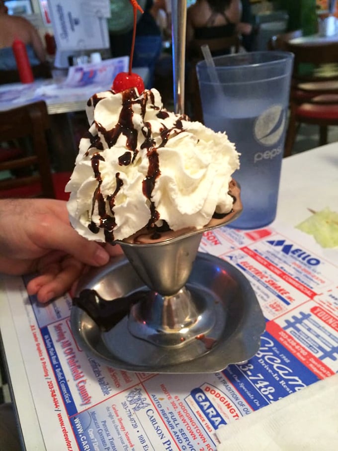 Ice cream sundae architecture at its finest&mdash;whipped cream peaks, chocolate rivers, and that essential cherry beacon on top.
