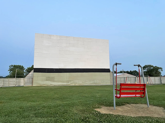 A splash of red against green&mdash;this classic swing set stands ready for young adventurers between double features.