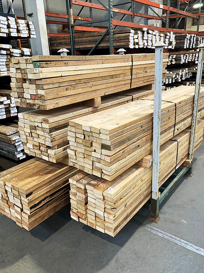 Lumber stacked with military precision. Each board carries the patina of its previous life and the potential for its next.