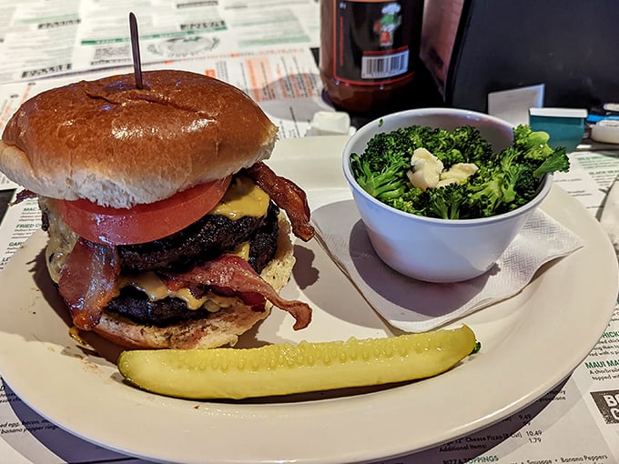 A burger that requires both hands, a stack of napkins, and possibly a signed liability waiver. The broccoli is just there for appearances.