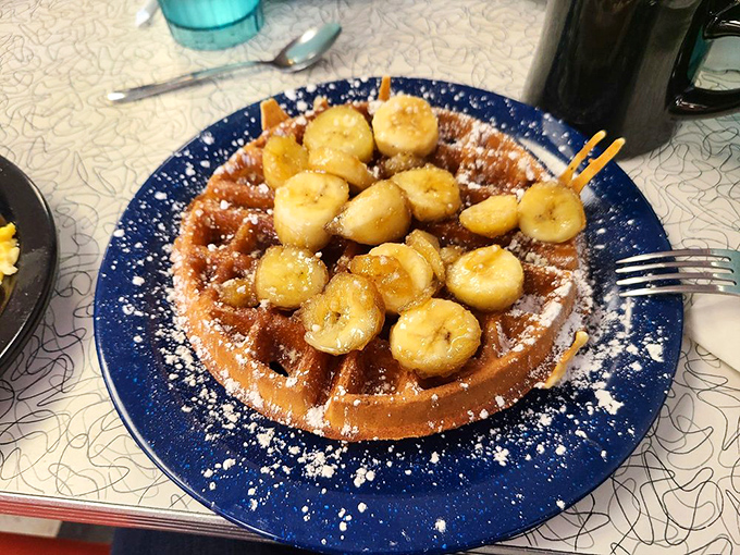 Bananas Foster waffle: where breakfast meets dessert and nobody complains. The powdered sugar snowfall is just showing off at this point.