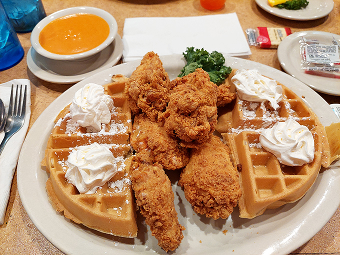 Chicken and waffles with a side of what appears to be butternut squash soup &ndash; sweet, savory, and crispy collide in perfect harmony.
