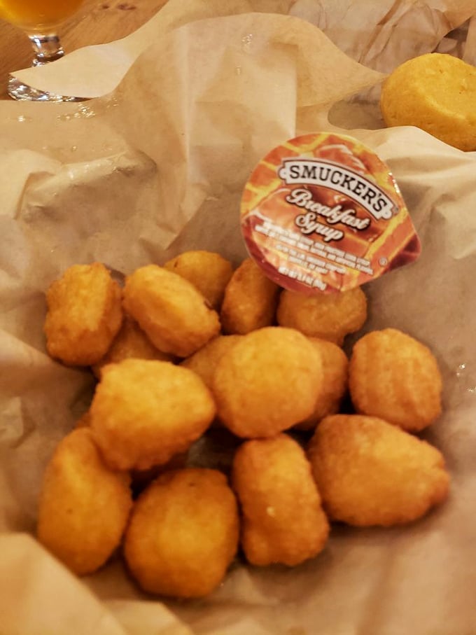 Golden-fried corn nuggets huddle together like tiny treasures. That Smucker's syrup cup suggests a sweet-savory adventure your taste buds never expected.