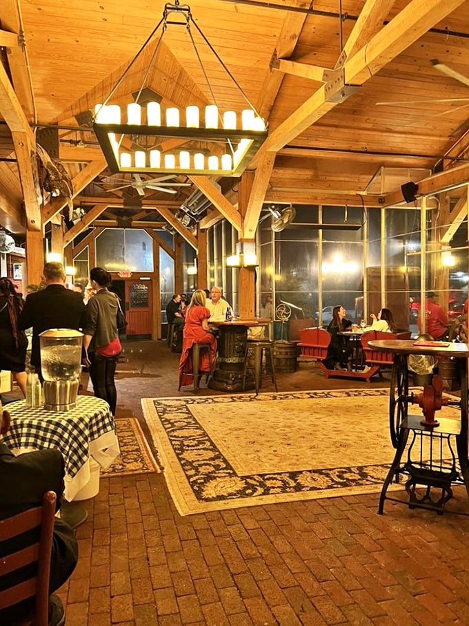 The dining area hums with conversation and laughter as guests savor meals under soaring wooden beams and warm, glowing chandeliers.