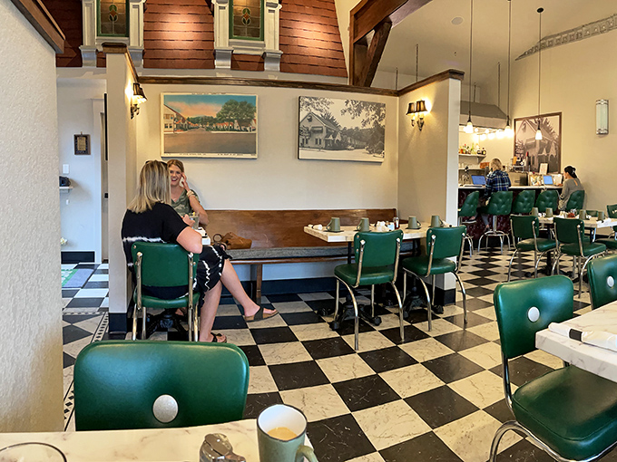 The green chairs against that classic checkered floor create a dining atmosphere where conversations flow as easily as the coffee.