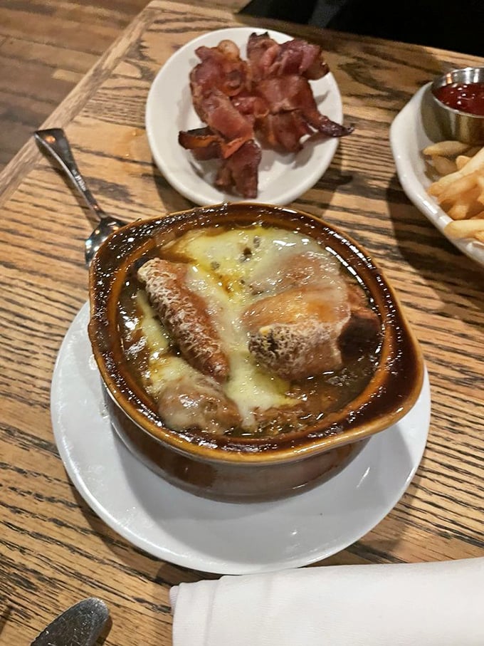 French onion soup that demands commitment – a gooey, molten blanket of cheese protecting a treasure of savory broth and tender onions below.