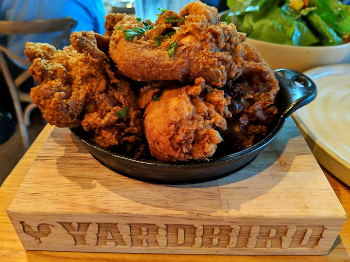 Fried chicken perfection served in cast iron on a wooden pedestal. Golden, crispy, and worthy of its throne-like presentation.