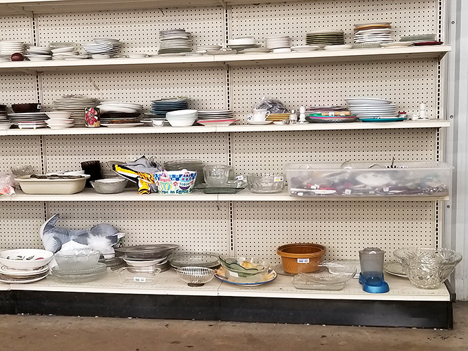 Plates and bowls stacked like geological layers, each shelf a cross-section of America's dining history from formal china to everyday Pyrex.
