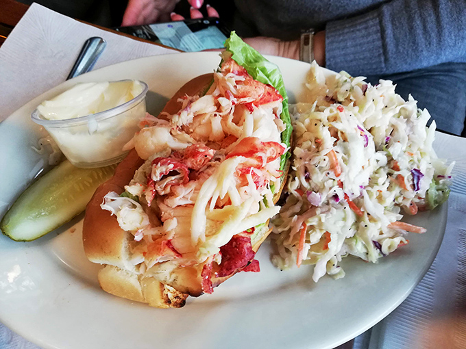 A perfectly dressed lobster roll flanked by a pickle spear and coleslaw&mdash;the coastal equivalent of a three-piece suit.