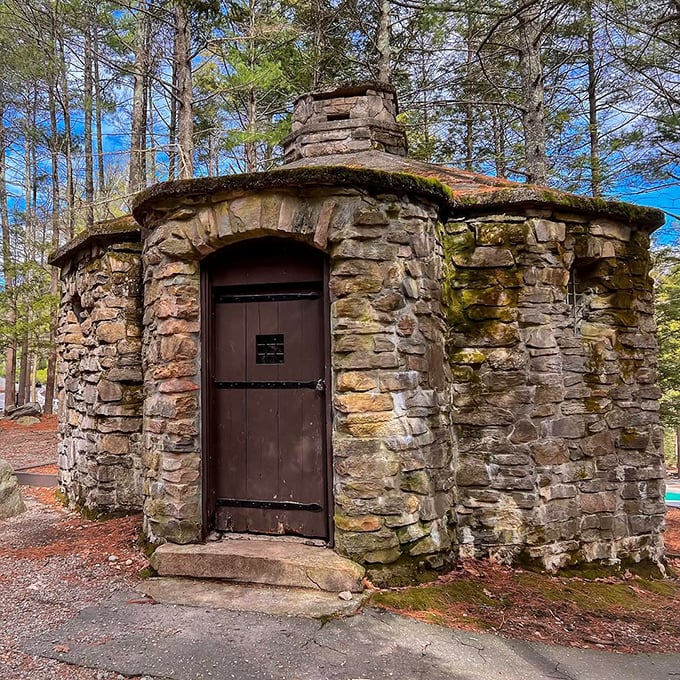 Admire the rustic charm of this sturdy stone building, featuring moss-covered walls and a dark wooden door tucked among trees.