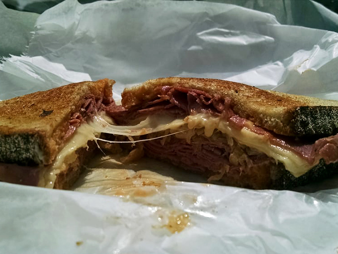 The Reuben, caught in a moment of melty, meaty glory &ndash; where corned beef, Swiss, and sauerkraut perform a perfect culinary tango.