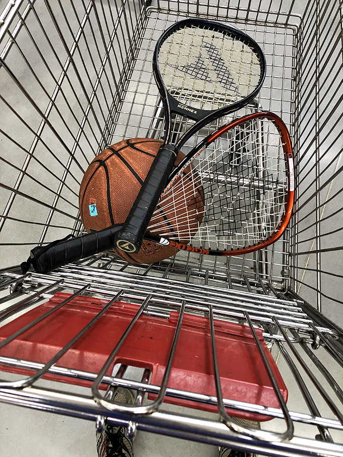 The ultimate shopping cart still life&mdash;tennis rackets and basketball proving that Village Discount is a sporting chance worth taking.