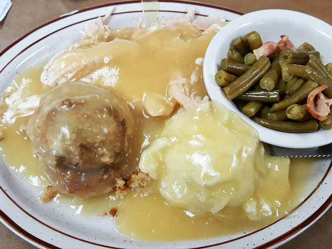 Turkey and dressing smothered in gravy with a side of green beans. This plate doesn't just say comfort food&mdash;it wraps you in a warm, gravy-soaked hug.