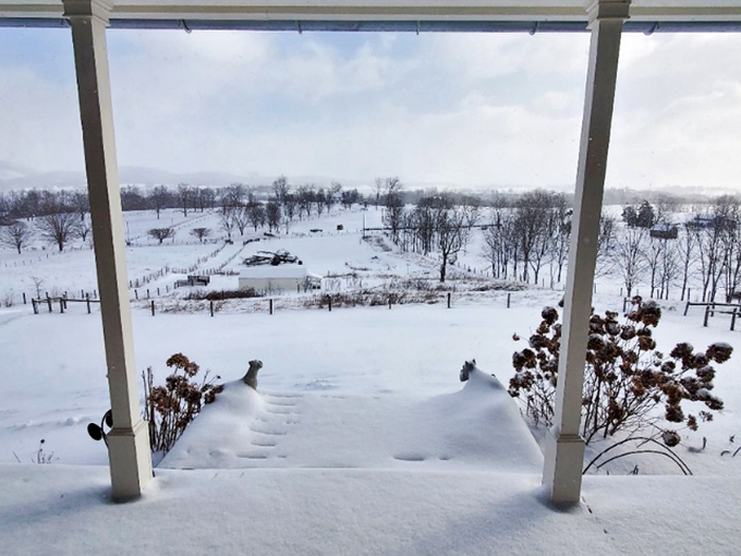Winter transforms Lewisburg into a pristine wonderland. From this porch view, the snow-blanketed landscape stretches toward mountains that frame the town like protective sentinels.