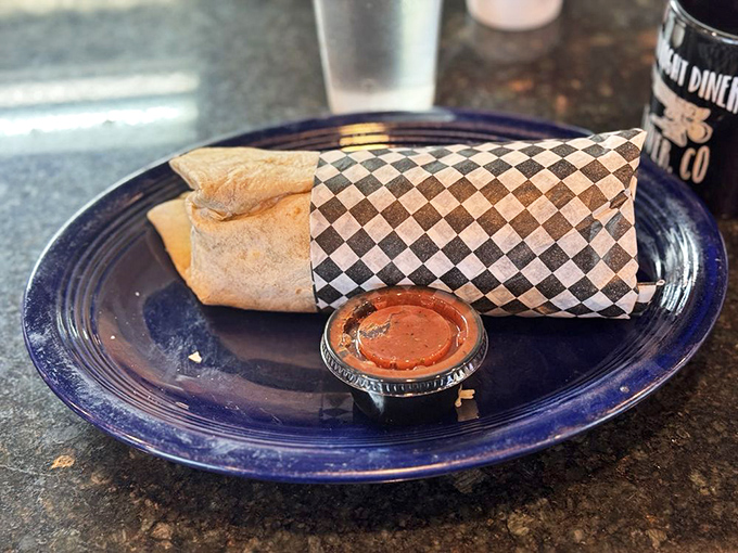 The humble wrap elevated to art form status, tucked into its checkered paper bed. That sauce cup isn't just condiment&mdash;it's liquid enhancement for an already spectacular hand-held feast.