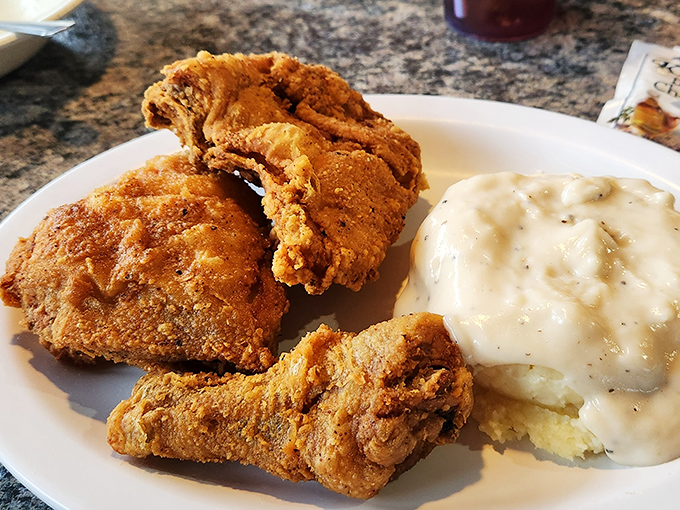 The holy trinity of comfort food: perfectly fried chicken, cloud-like mashed potatoes, and gravy that should be bottled and sold as therapy.