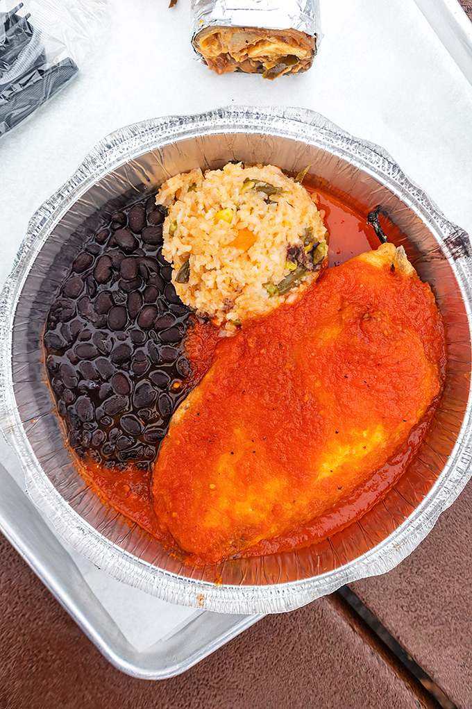 A trio of perfection &ndash; black beans, Spanish rice, and a chile relleno swimming in vibrant sauce. This plate doesn't need fancy presentation to impress.