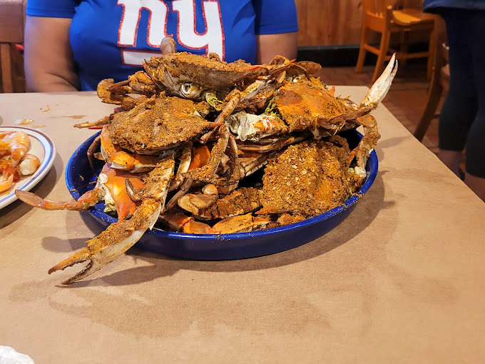 The blue bowl of destiny arrives—steamed crabs piled high, their Old Bay-crusted shells practically daring you to work for your dinner.