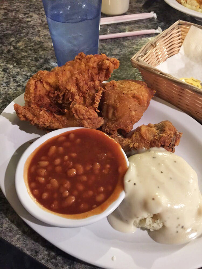 Behold the crispy trinity: golden chicken, hearty baked beans, and mashed potatoes with gravy that could solve world peace, if only temporarily.