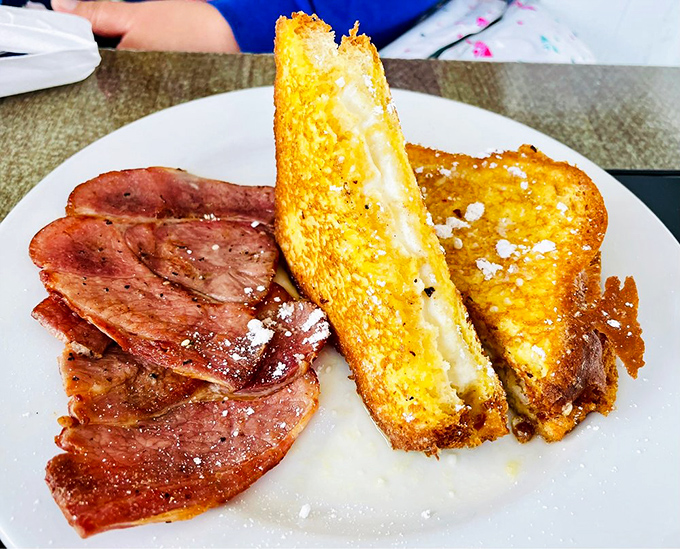 The French toast cross-section reveals its creamy secrets. That golden exterior crunch should be classified as a symphony.
