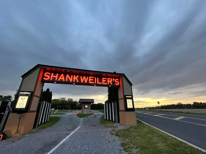 The entrance gate stands sentinel against a dramatic sky, the threshold between ordinary life and the magic of outdoor cinema.