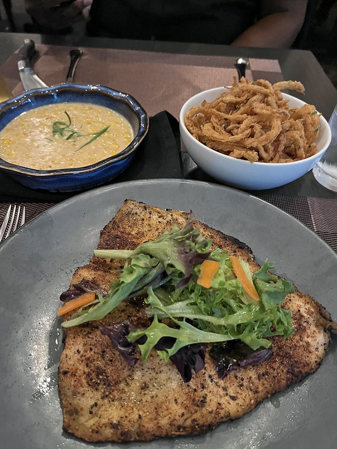 Perfectly grilled trout with a side of creamed corn that looks like sunshine in a bowl and crispy onions providing textural fireworks.
