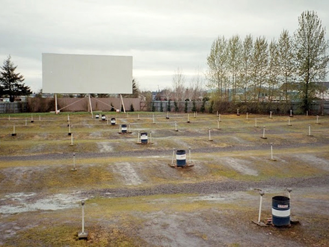 Those speaker poles stand like sentinels in an empty lot, patiently waiting for cars to arrive and movies to begin.