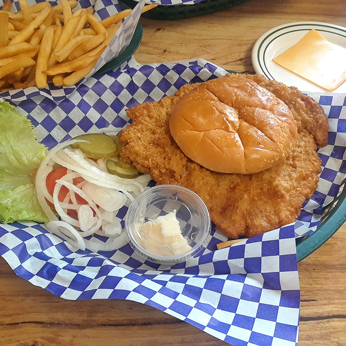The pork tenderloin sandwich—where the meat decided the bun was merely a suggestion. Midwest portion sizes in their natural habitat.