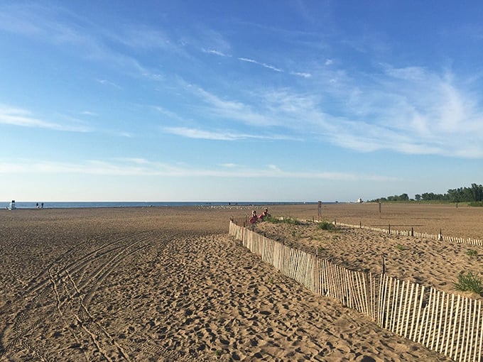 The beach stretches toward the horizon, protected by natural fencing that helps preserve the delicate dune ecosystem behind the sandy playground.