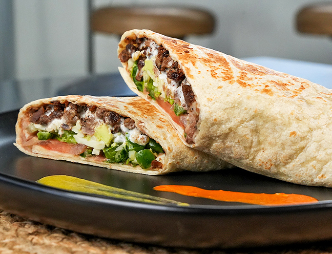 This isn't just a burrito&mdash;it's a masterclass in balance. The slight char on the tortilla, the peek of green, the promise of seasoned meat within&mdash;perfection.